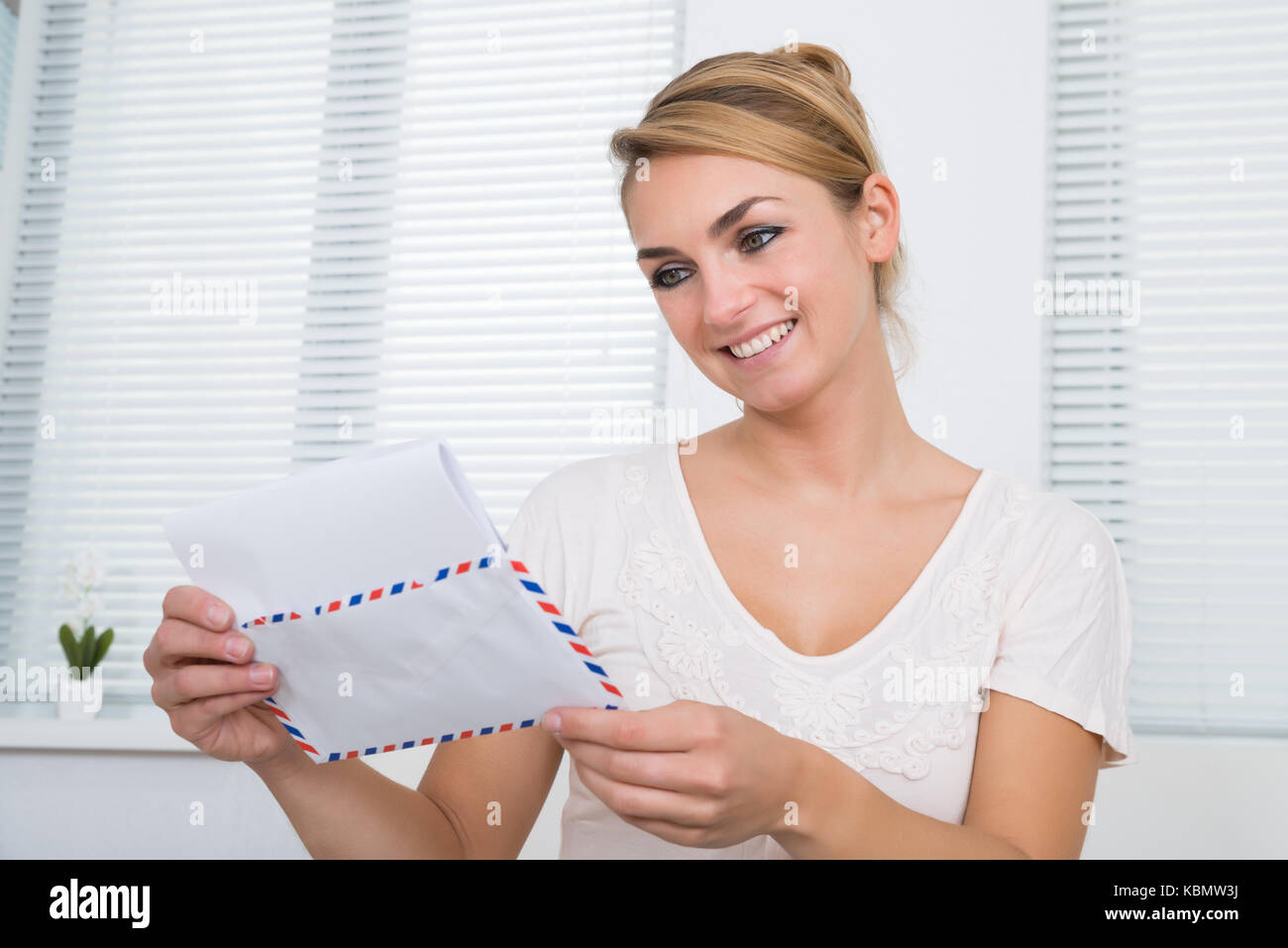 Happy young woman reading letter while sitting at home Stock Photo - Alamy