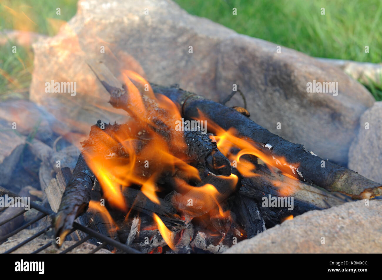 close on flame of campfire between stones on the grass Stock Photo - Alamy