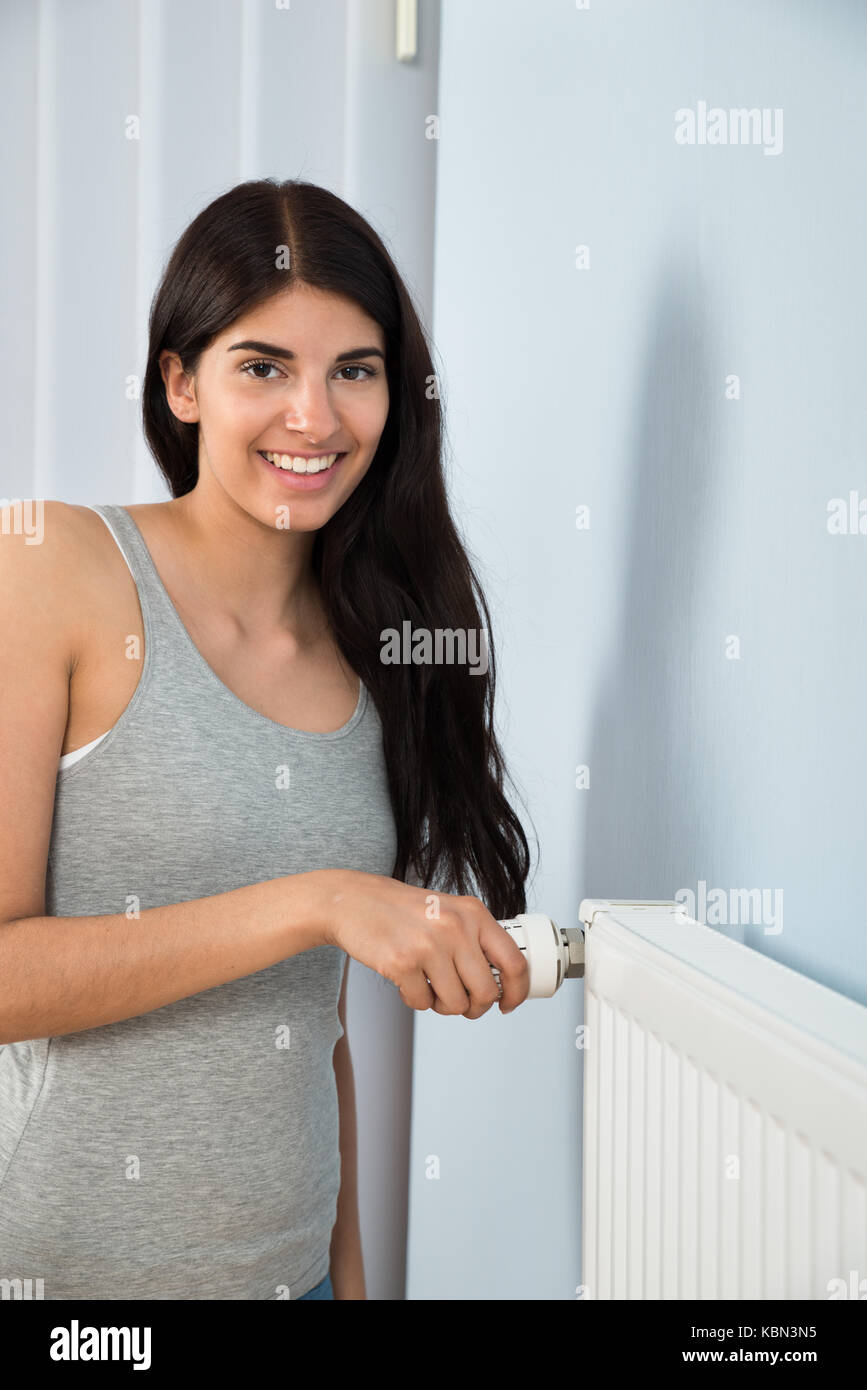 Young Happy Woman Adjusting Thermostat On Radiator At Home Stock Photo ...