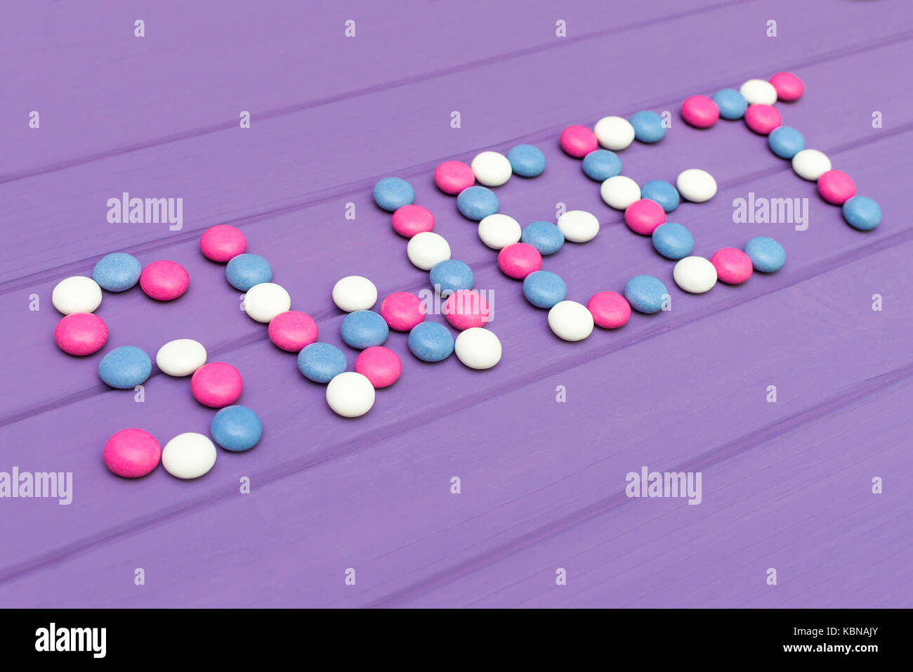 Image of word Sweet made of colorful candies on violet background. Copy ...