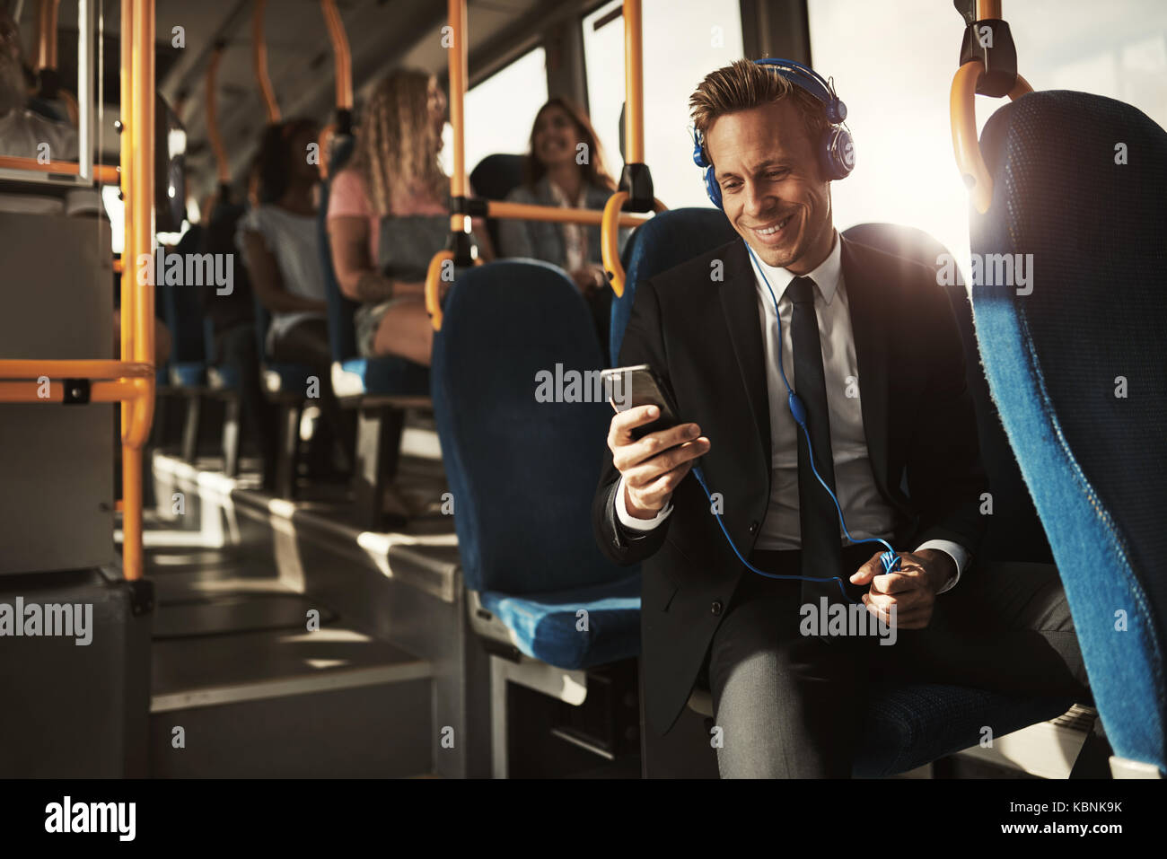 Smiling young businessman wearing a suit sitting on a bus during his ...
