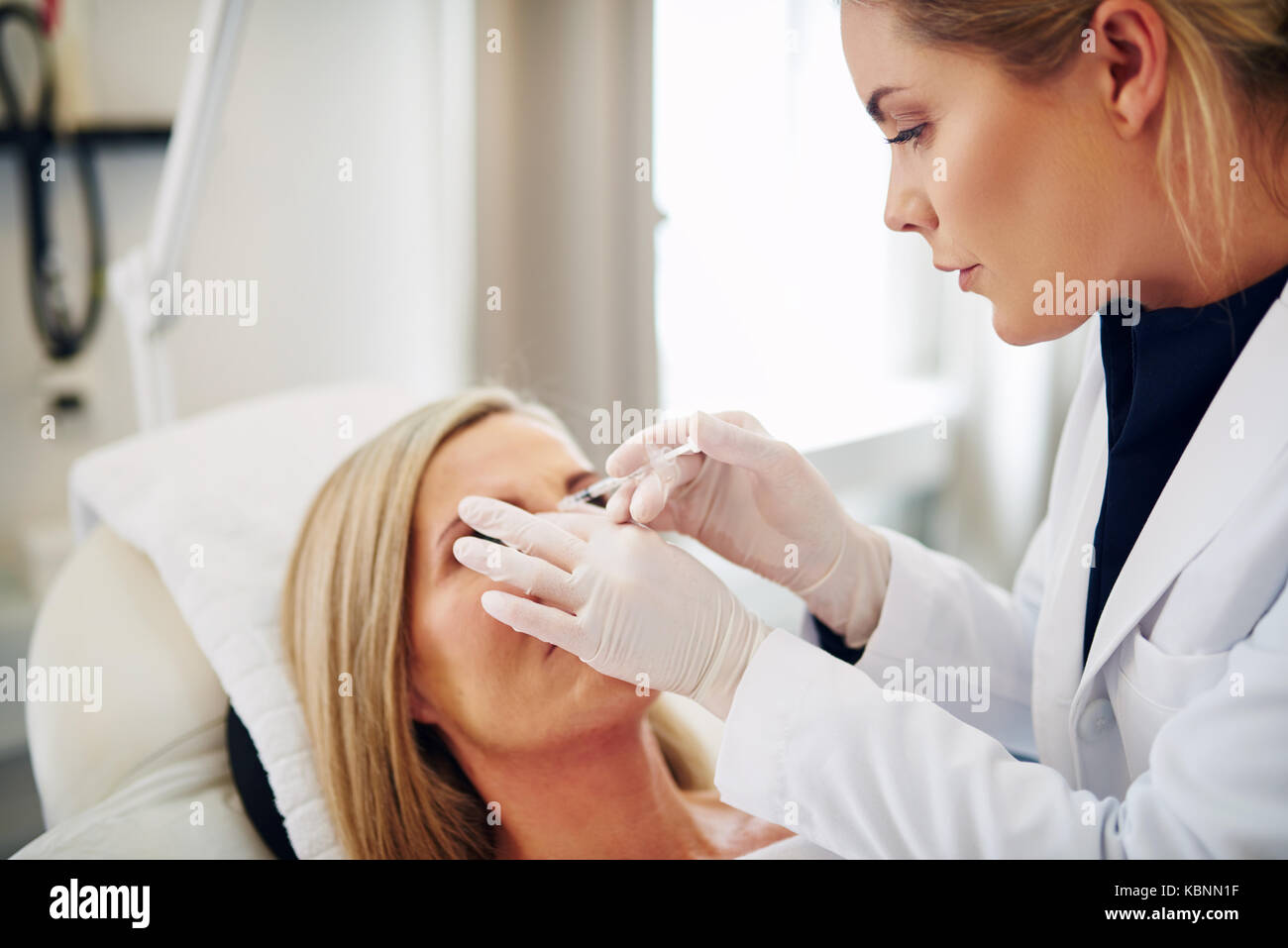 Young female doctor focused on performing a botox treatment to the ...