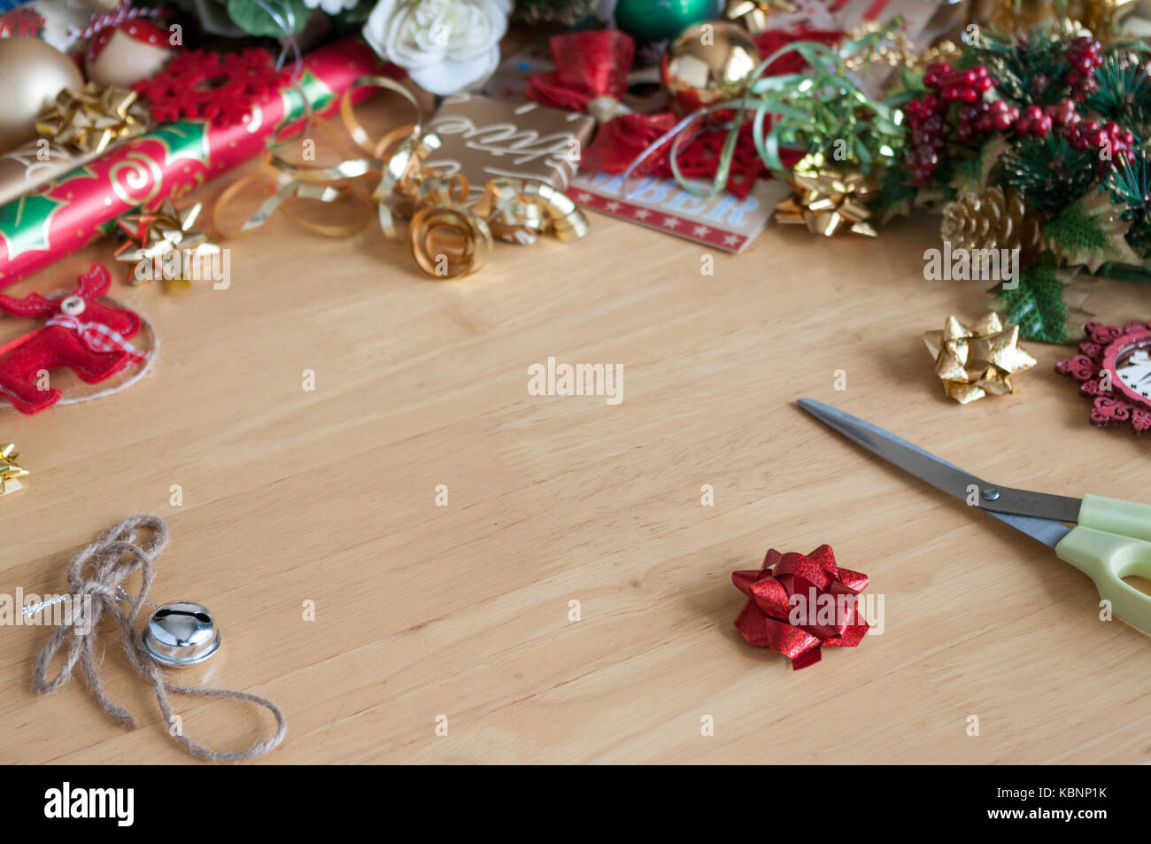 Gift wrapping and Christmas decorations forming a border on light wood ...