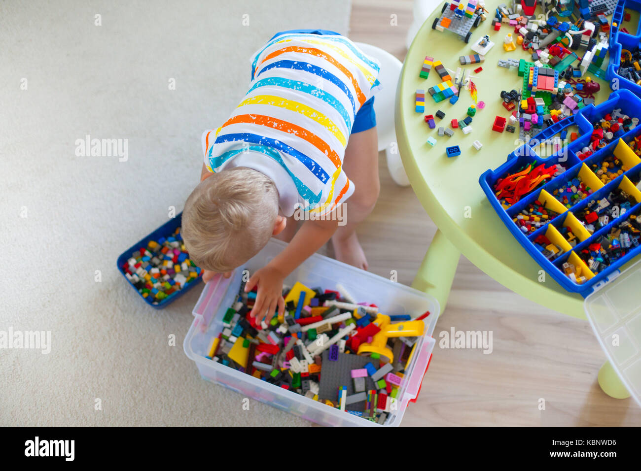 Little blond kid boy playing with lots of colorful plastic blocks ...