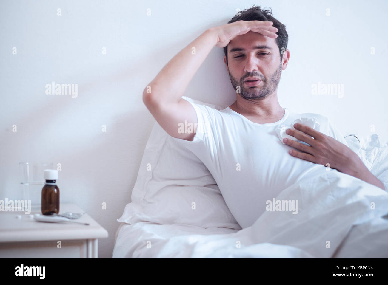 Sick man in bed measuring temperature and feeling fever Stock Photo - Alamy