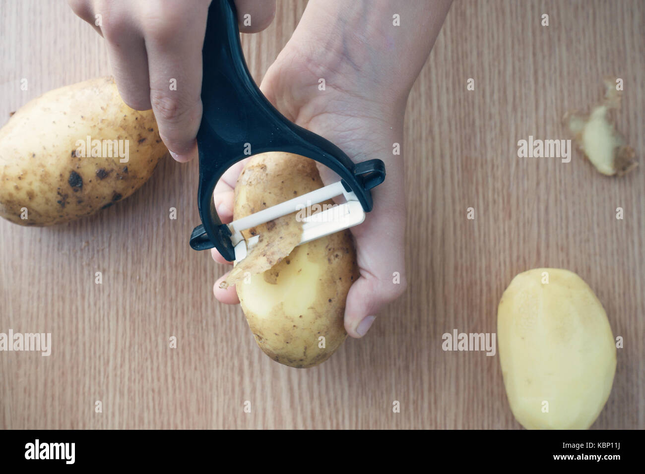 Hands peeling potato with black peeler Stock Photo - Alamy