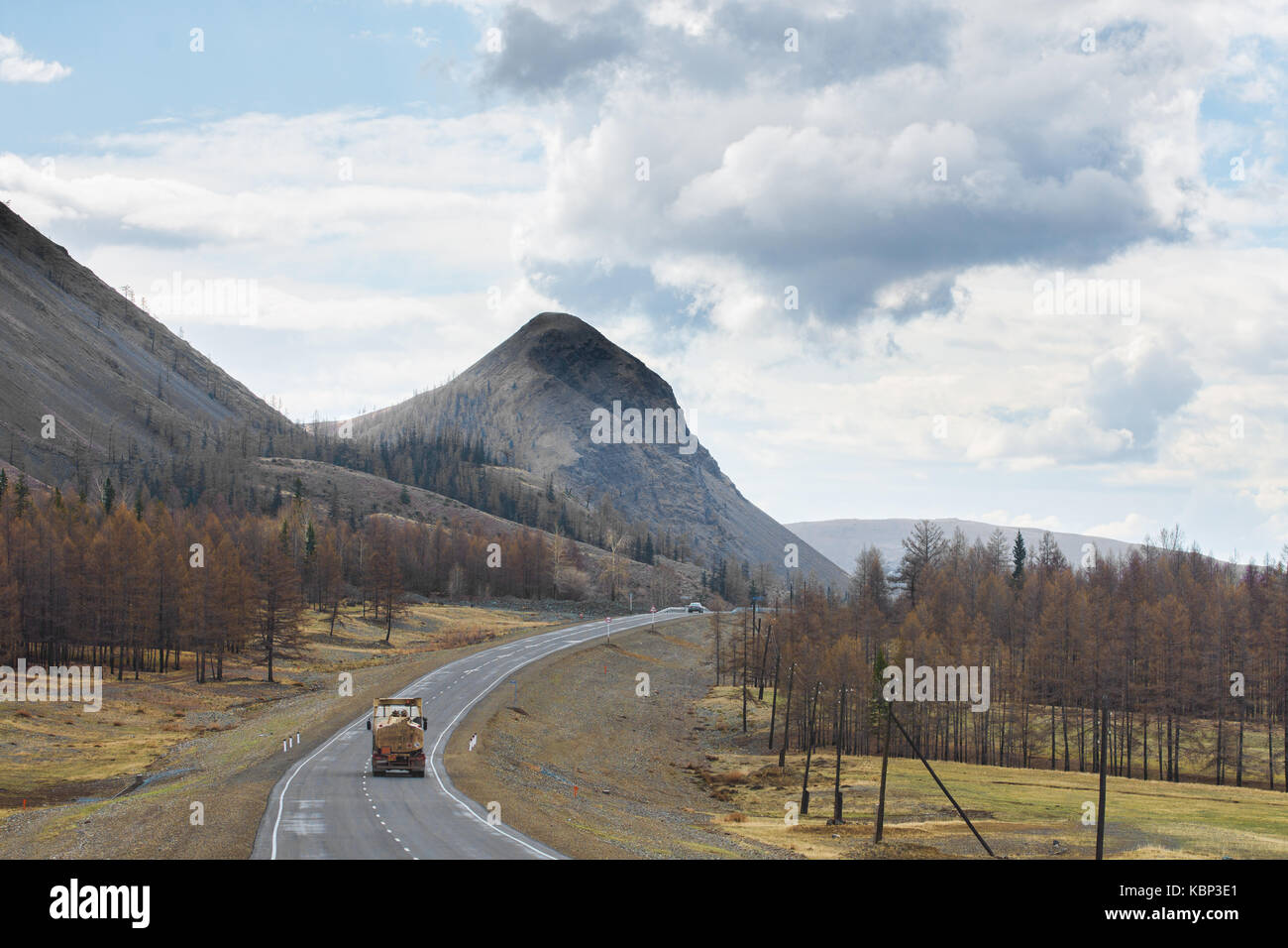 car driving on road at root of mountains and fluffy clouds on sky Stock ...