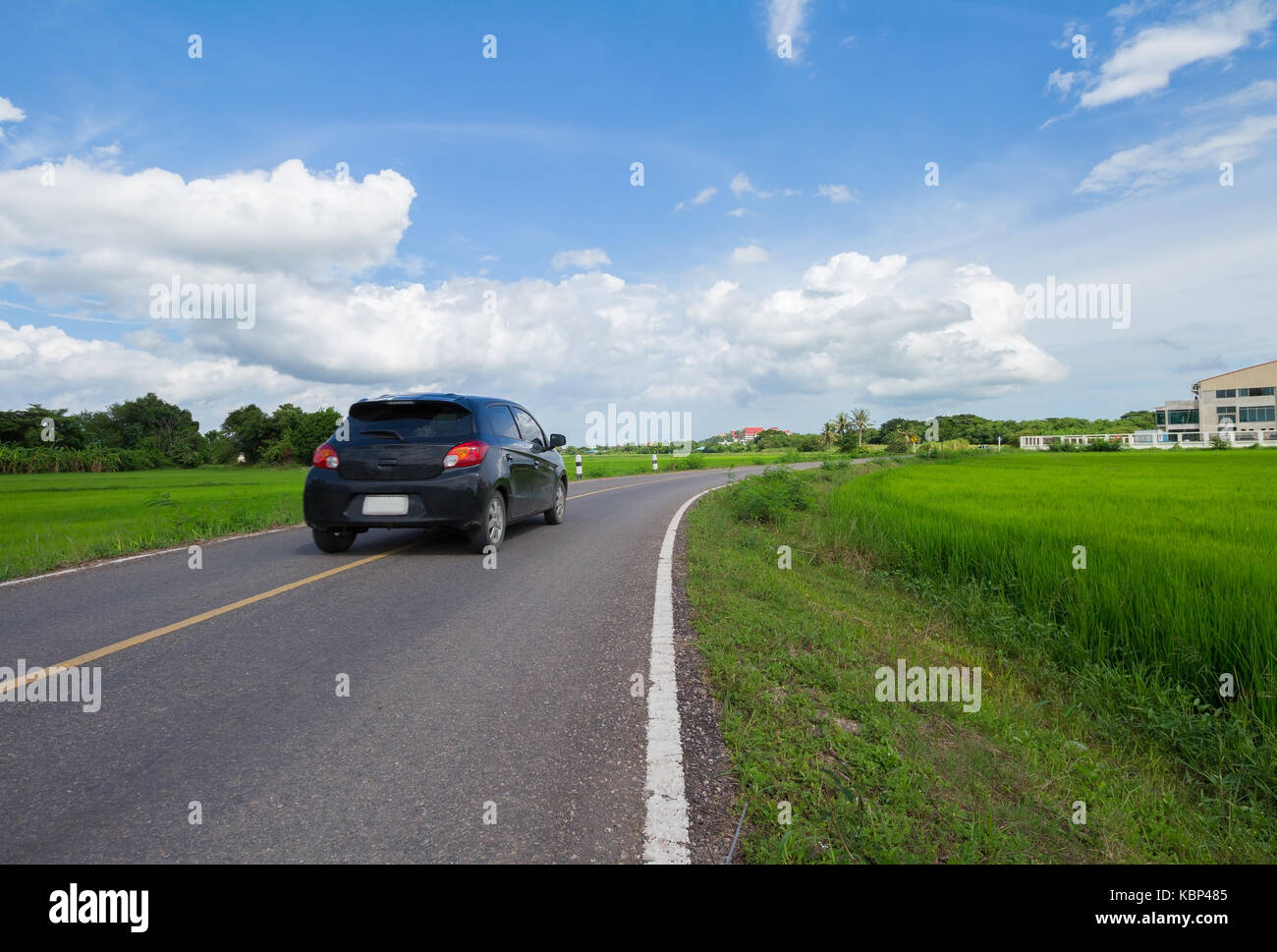A black car on the road that pass trough green rice field for adv or ...
