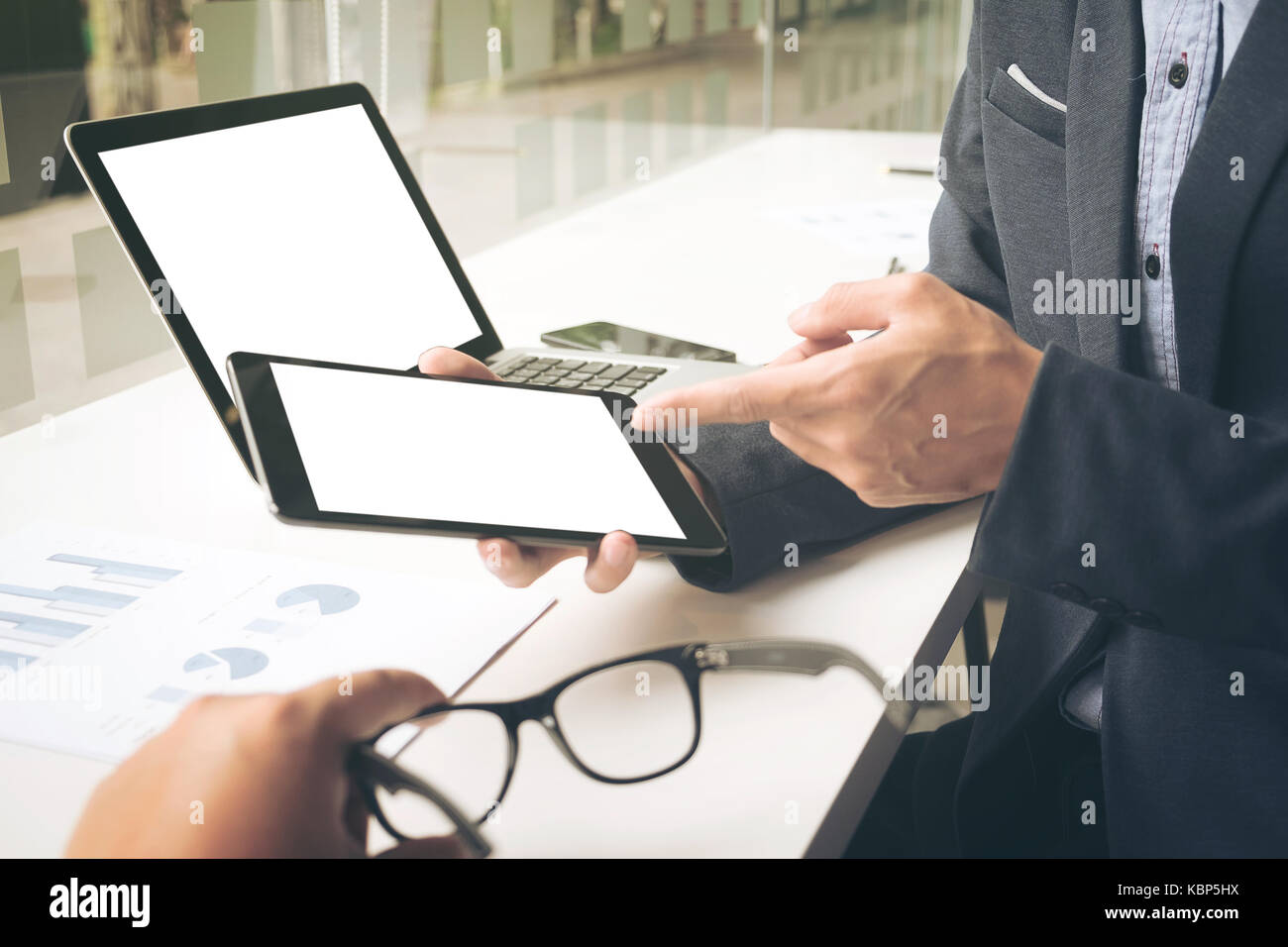 Close-up of male hand, using tablet and computer laptop while sitting ...