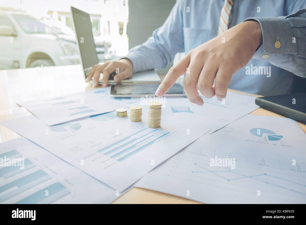 Close-up of Businessman pointing coin to rising stack of coins ...
