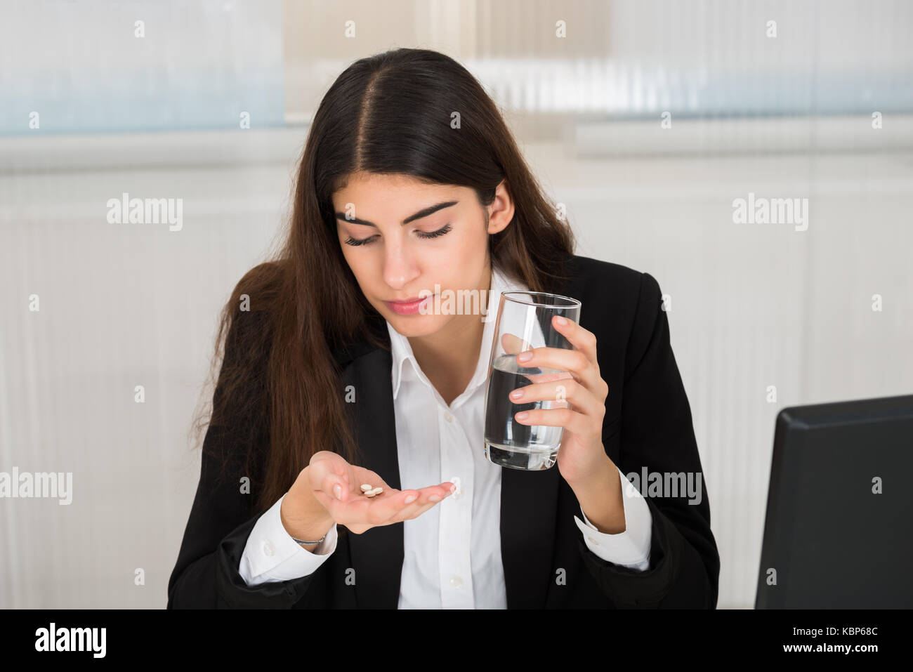 Young businesswoman taking medicine at work place in office Stock Photo ...