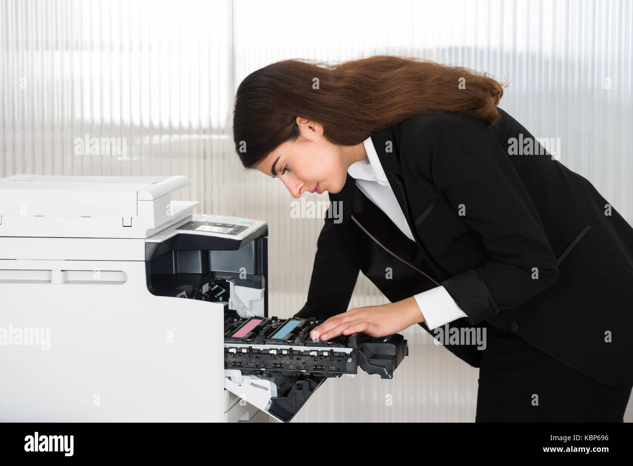 Side view of young businessman fixing cartridge in photocopy machine at ...