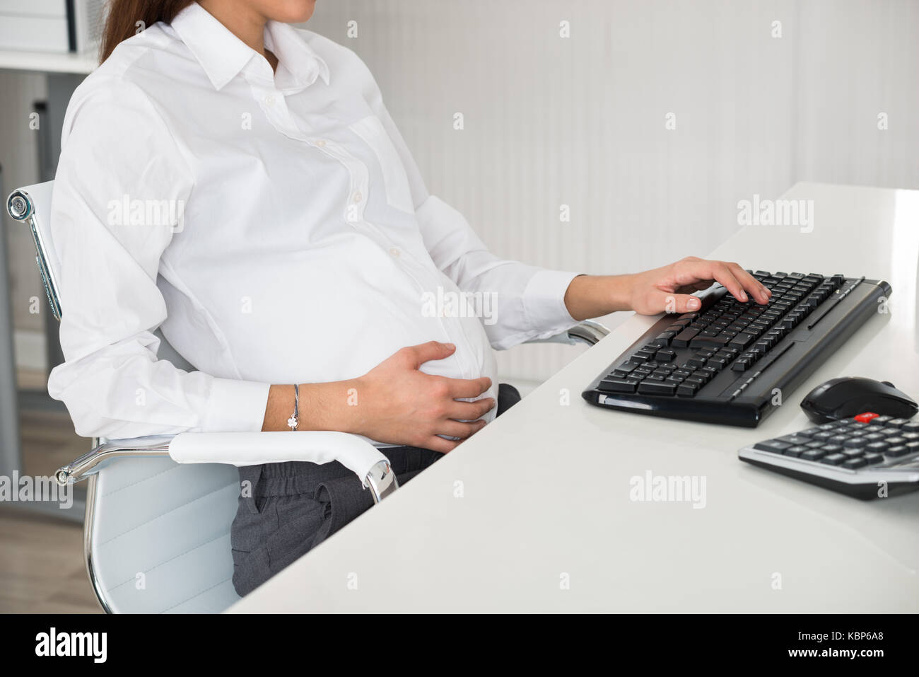 Side view midsection of pregnant businesswoman using computer at desk ...