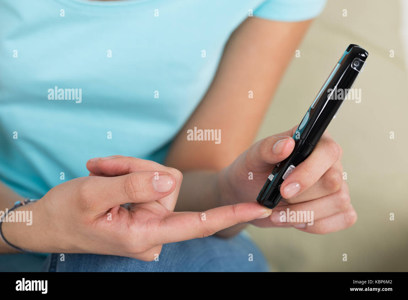Midsection of young woman using glucometer to check blood sugar level ...