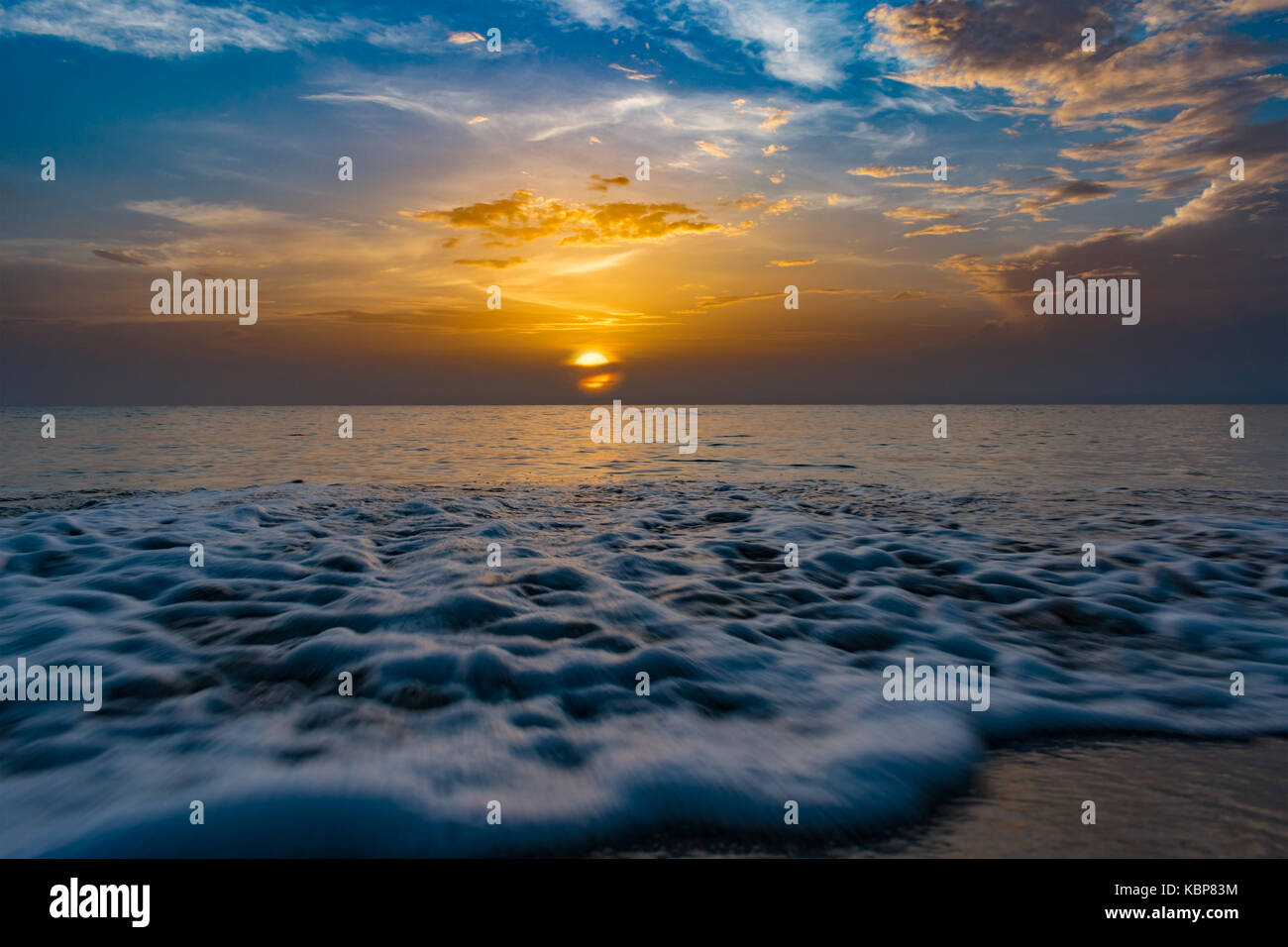close up of moving waves with the sun rising over the ocean on a calm ...