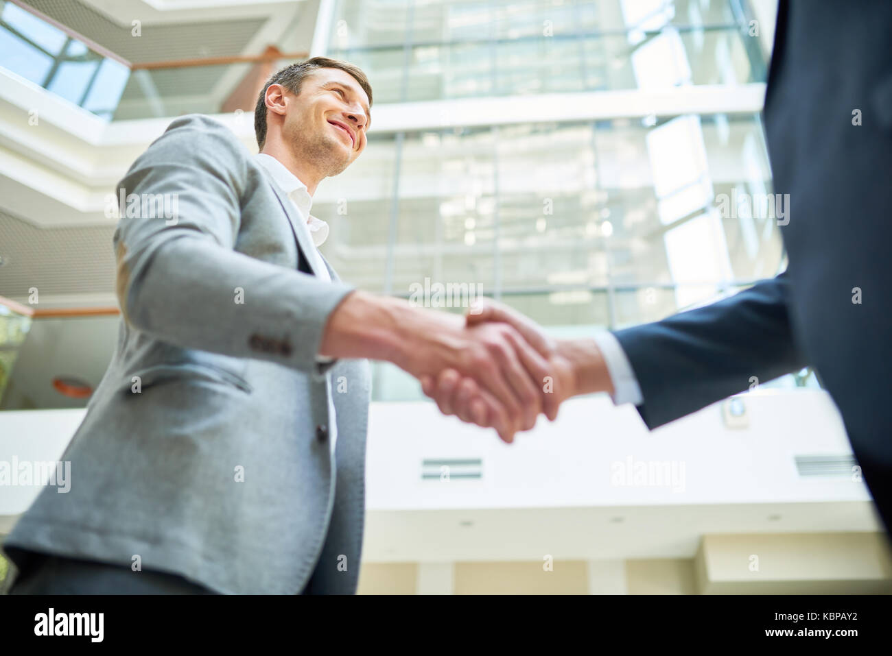 Low angle view of smiling business partners shaking hands while ...