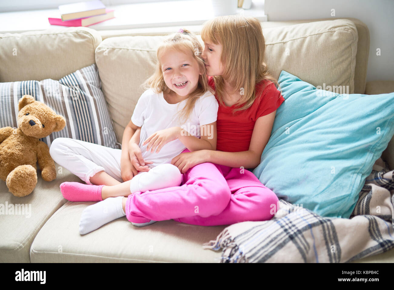 Portrait of two happy little sisters cuddling tenderly sitting on ...