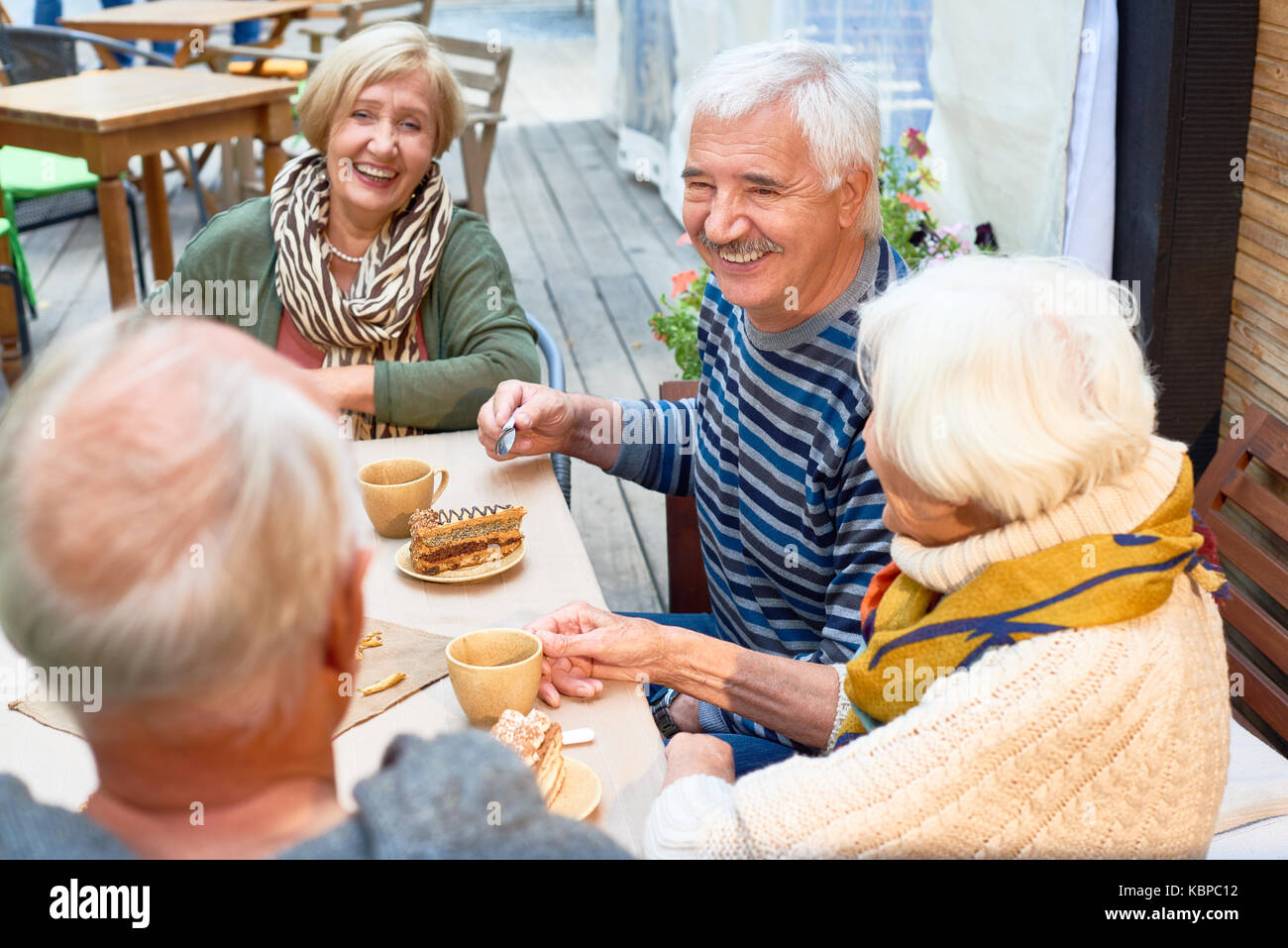 Joyful elderly friends having tea party at lovely outdoor cafe: they ...