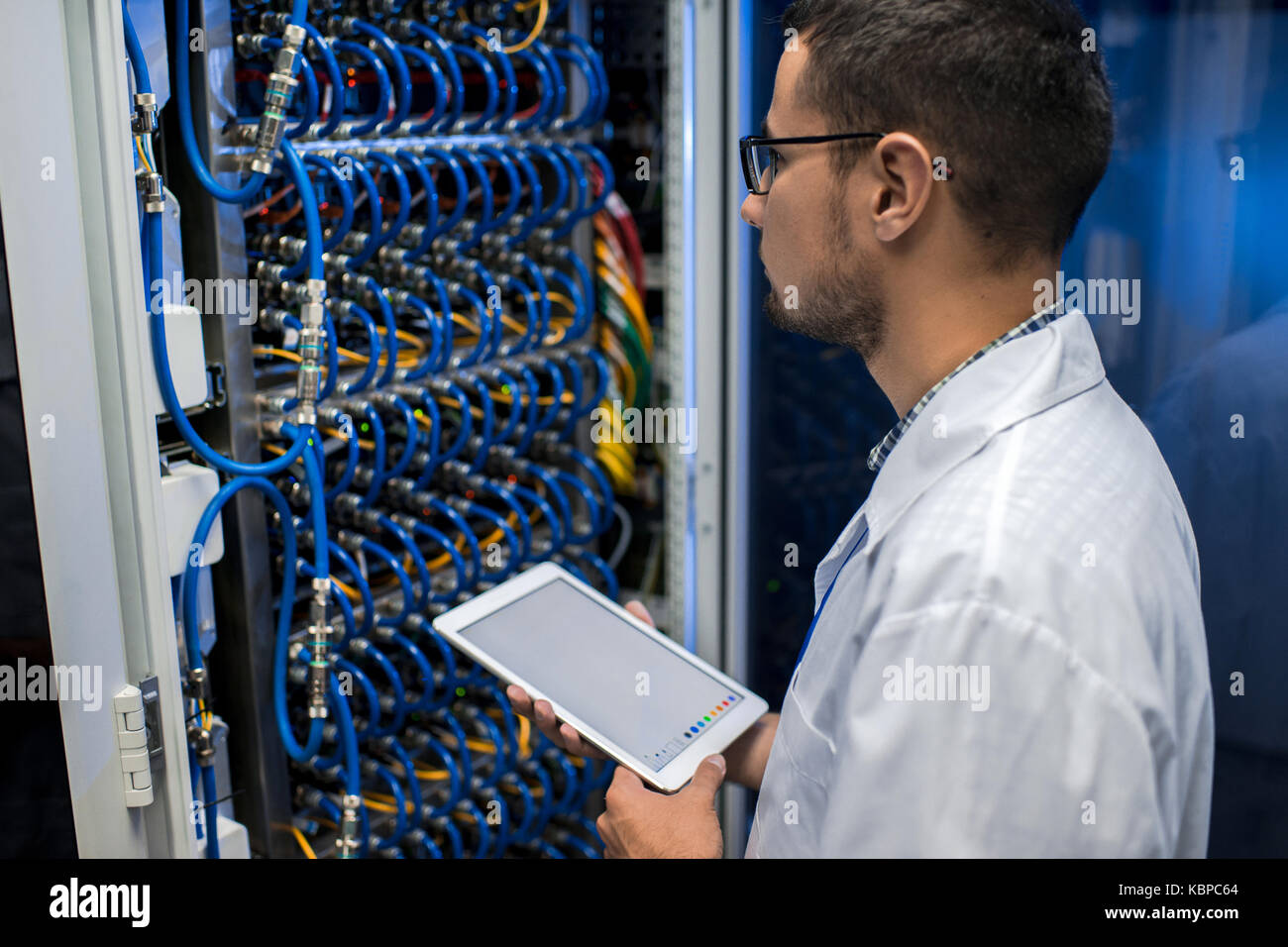 Portrait of young man holding digital tablet standing by supercomputer ...