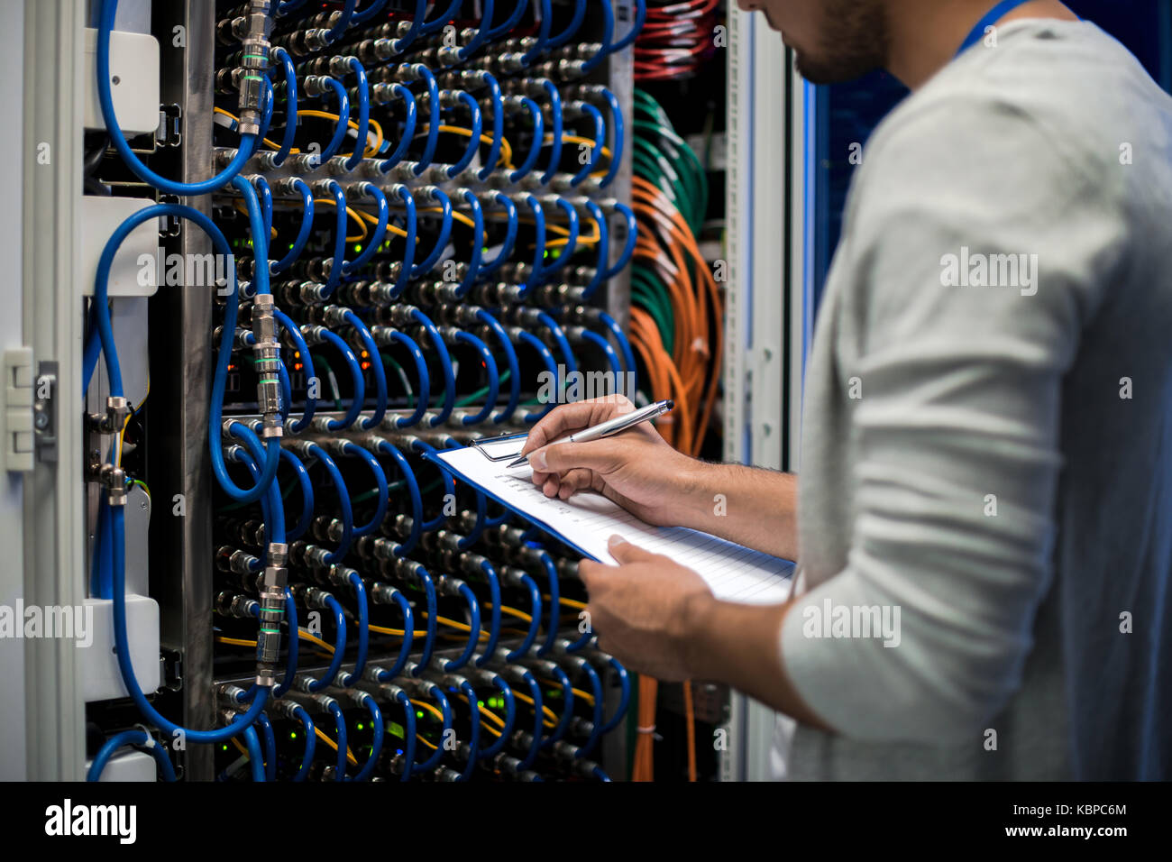 Closeup portrait of young man writing on clipboard standing by blade ...