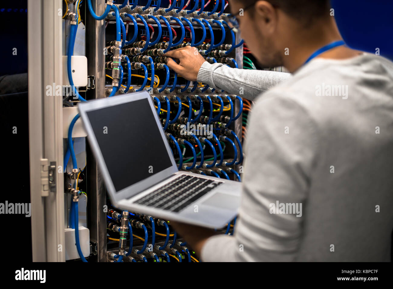 Back view portrait of young man working with supercomputer connecting ...