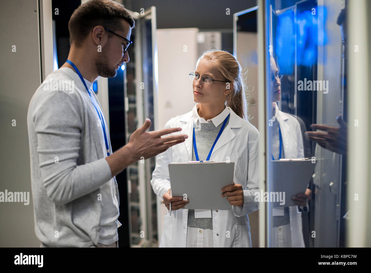 Portrait of two scientists, man and woman, standing by server cabinets ...