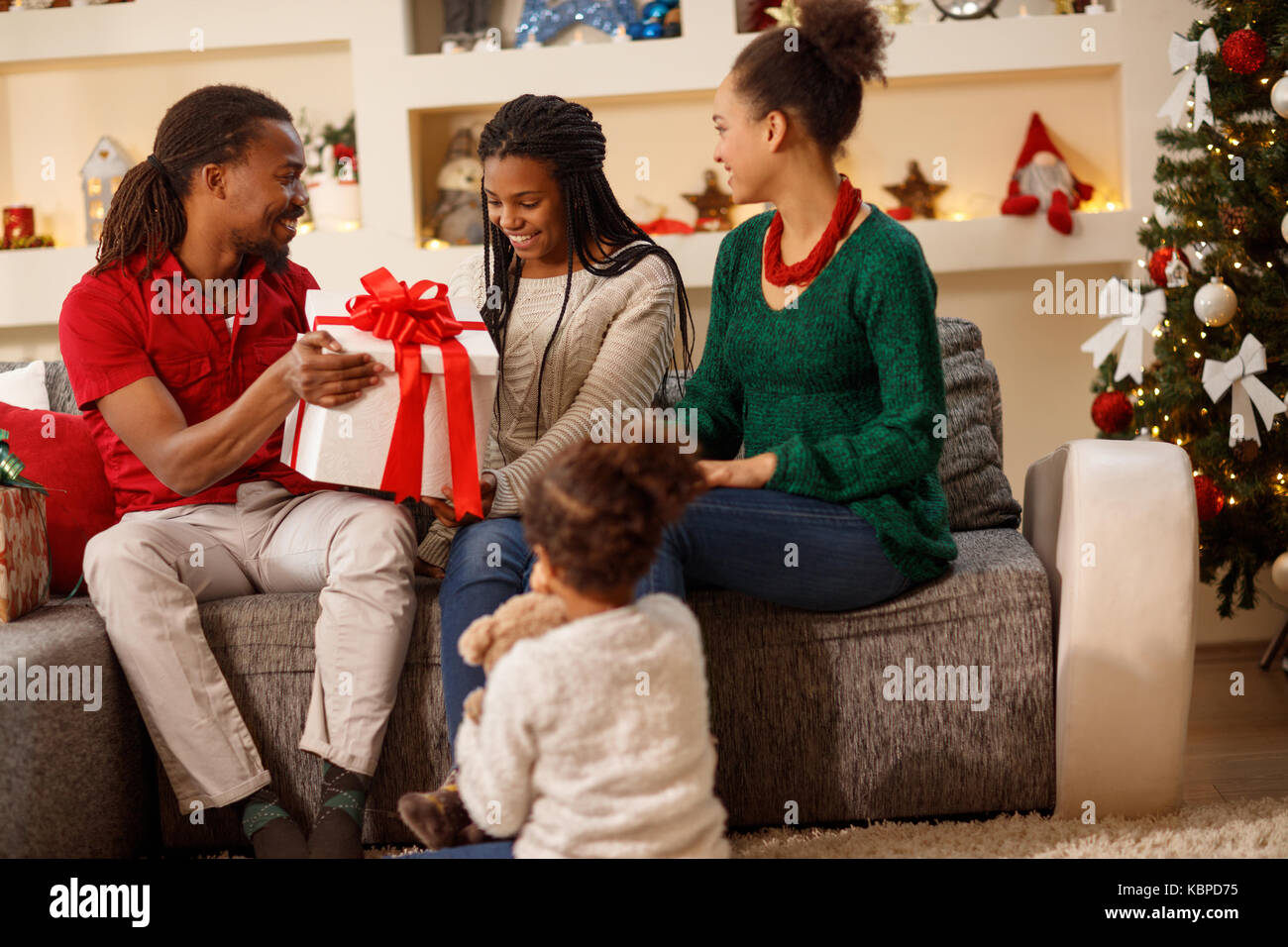Young happy family together with Christmas present Stock Photo - Alamy