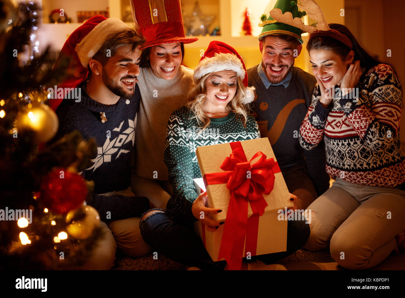 Surprised smiling woman and friends with Christmas gift in opening box ...