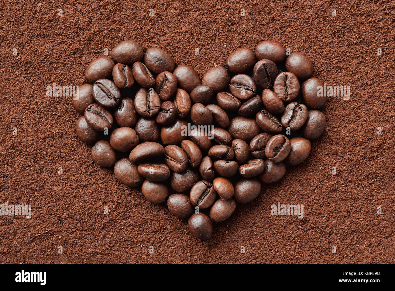 Coffee beans heart on coffee powder background Stock Photo - Alamy