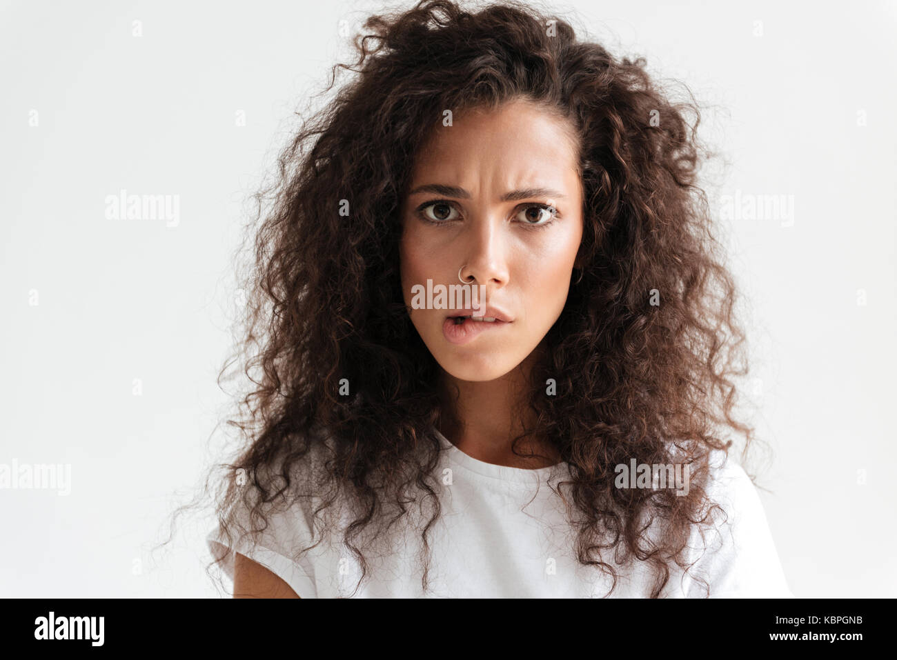 Portrait of an upset young woman with curly hair looking at camera ...