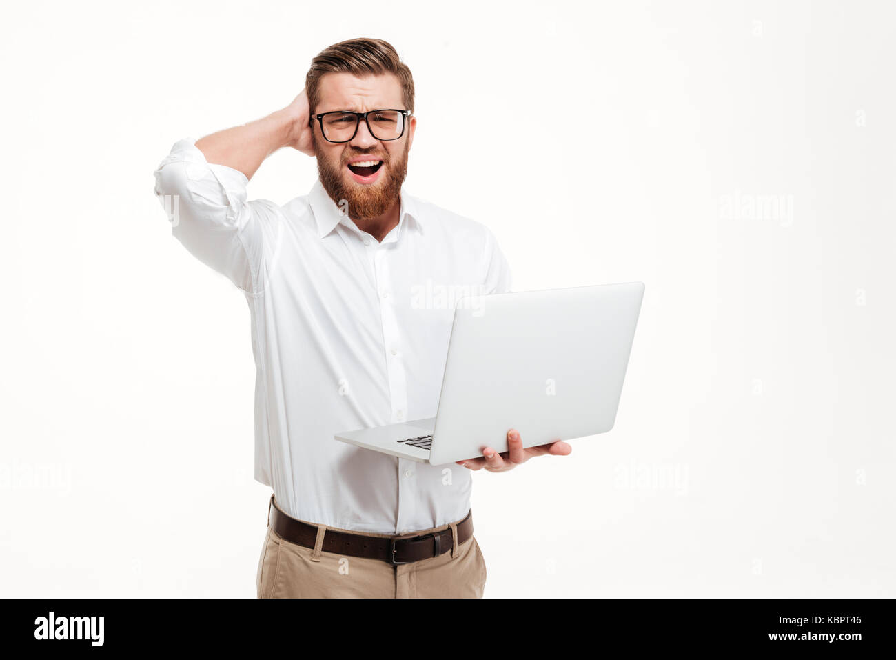 Confused young bearded man holding laptop computer and scratching his ...