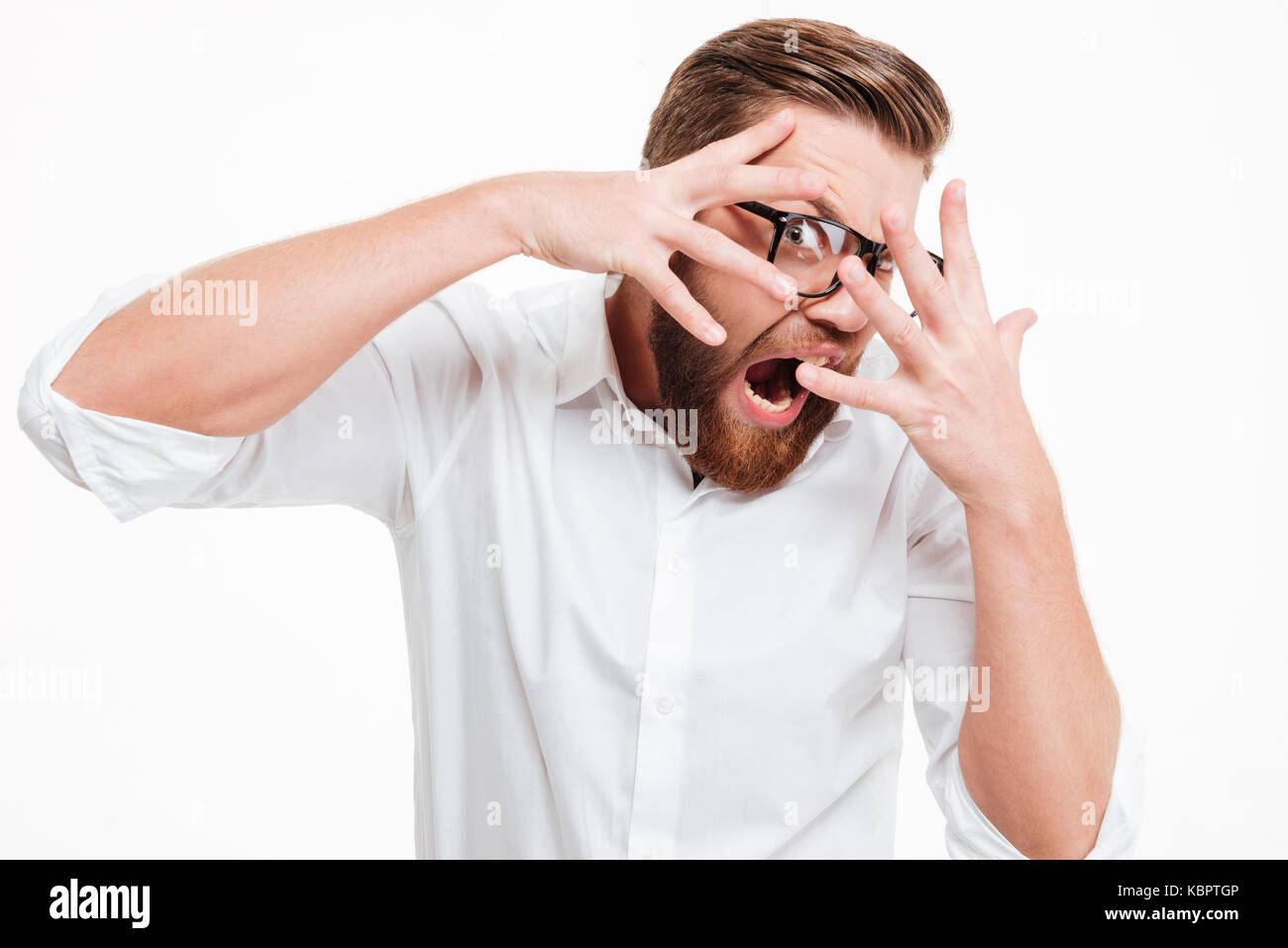 Picture of screaming scared young bearded man standing over white wall ...