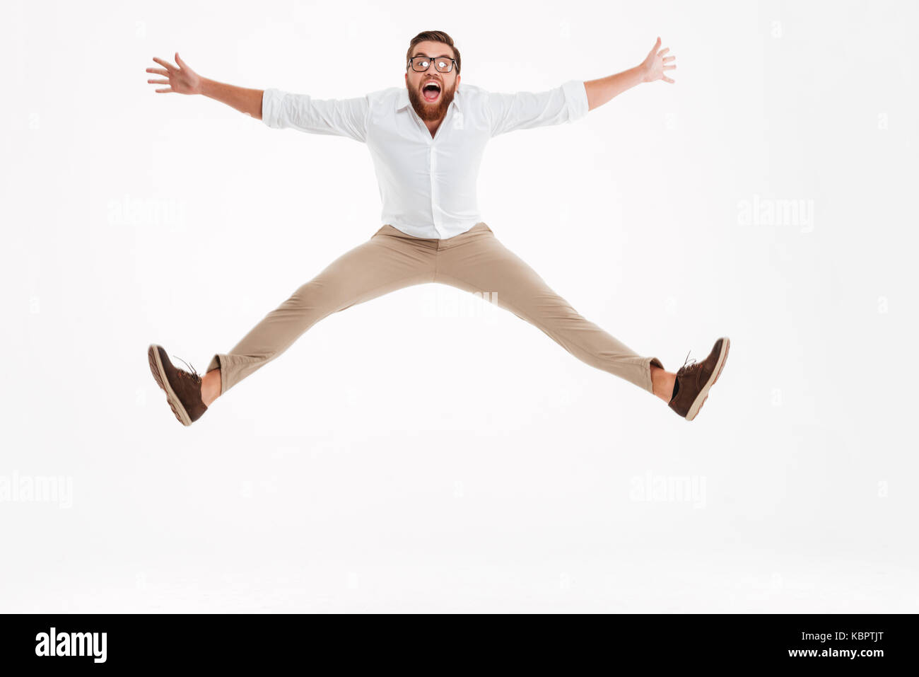 Photo of cheerful young bearded man jumping over white wall background ...