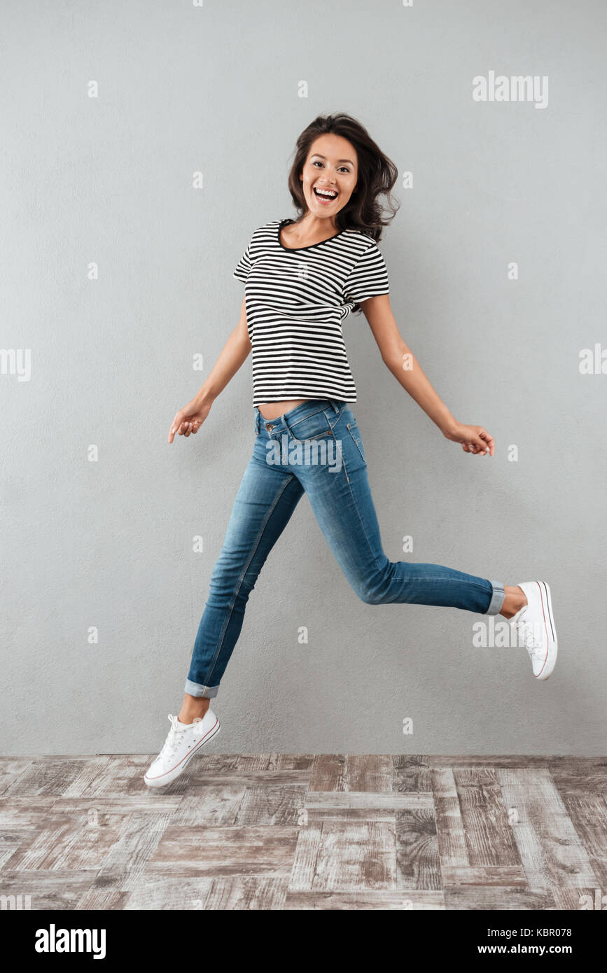 Full length portrait of a happy smiling asian woman jumping isolated ...