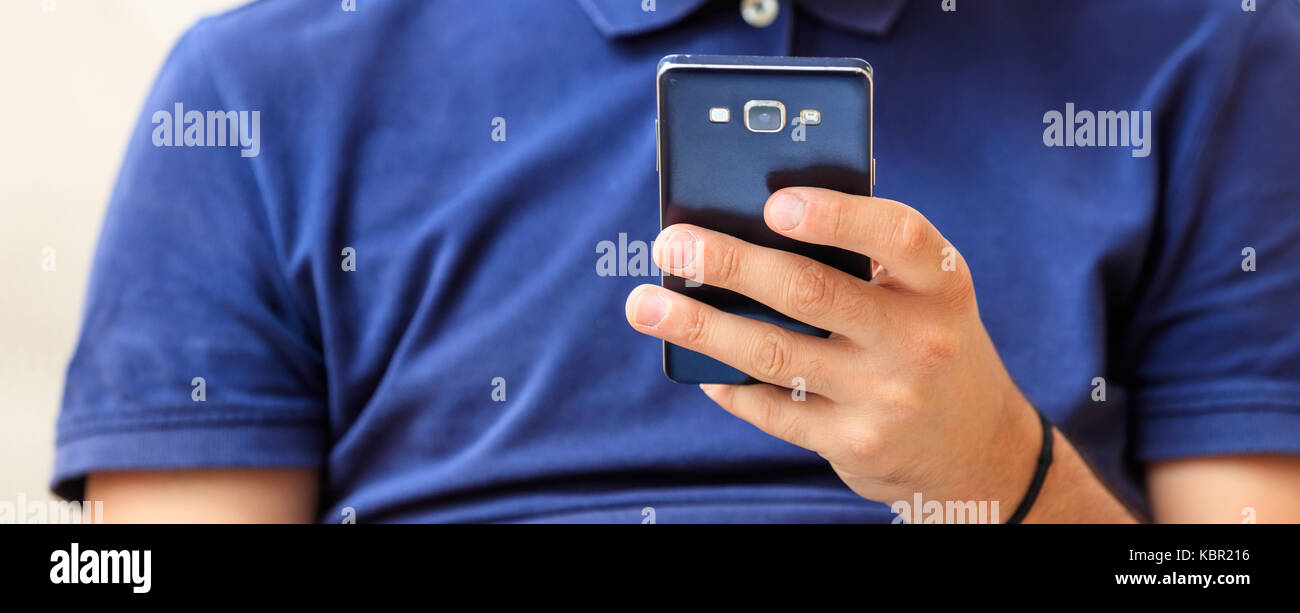 Young man looking at his smart phone, closeup on the hands Stock Photo ...