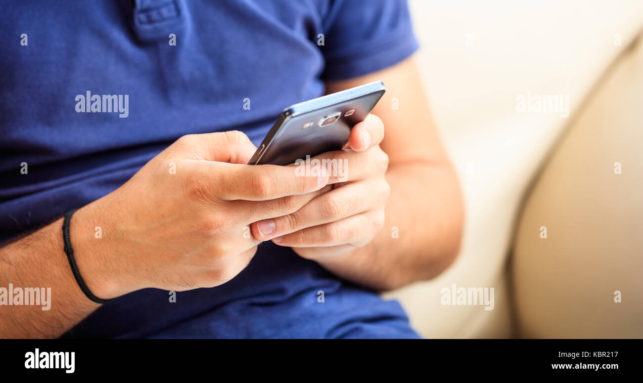 Young man looking at his smart phone, closeup on the hands Stock Photo ...