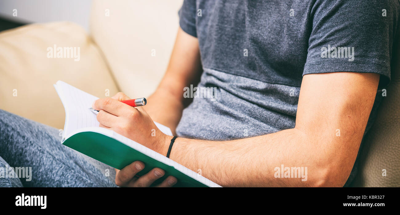 Modern workspace at home. Young left handed man making notes, sitting ...