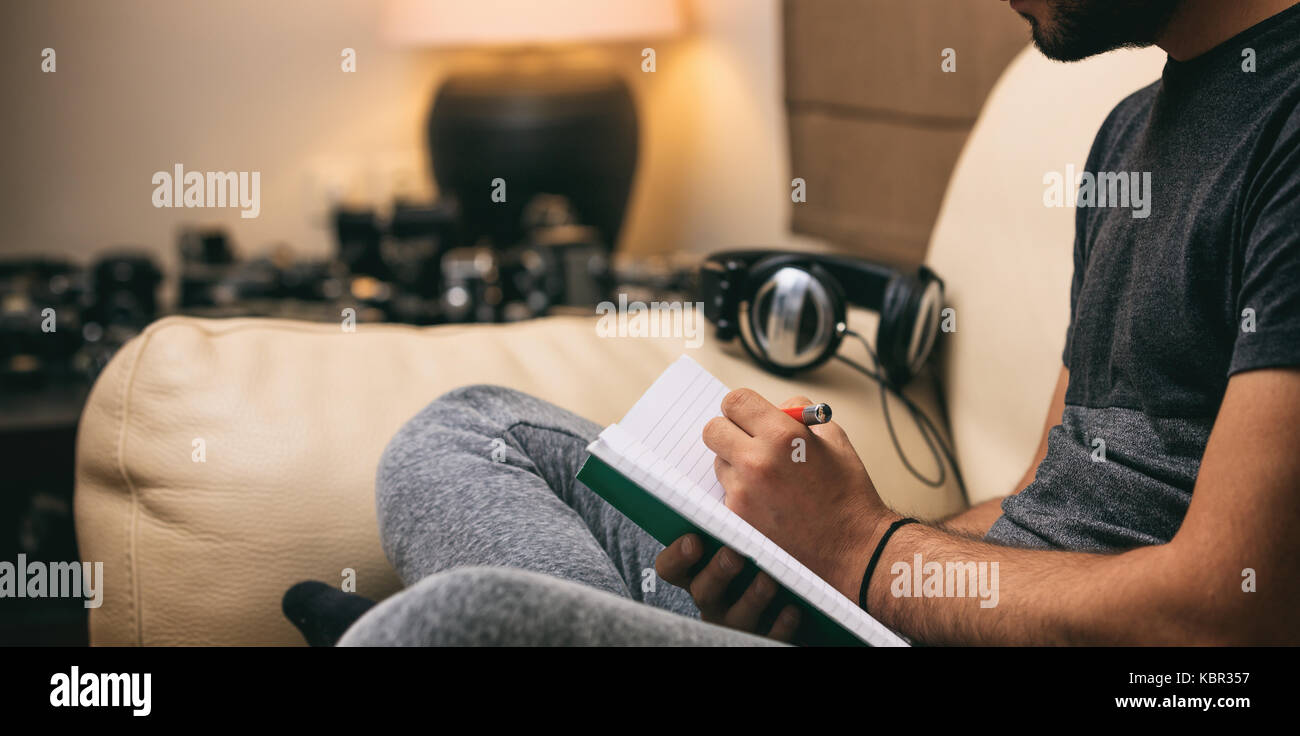 Modern workspace at home. Young left handed man making notes, sitting ...