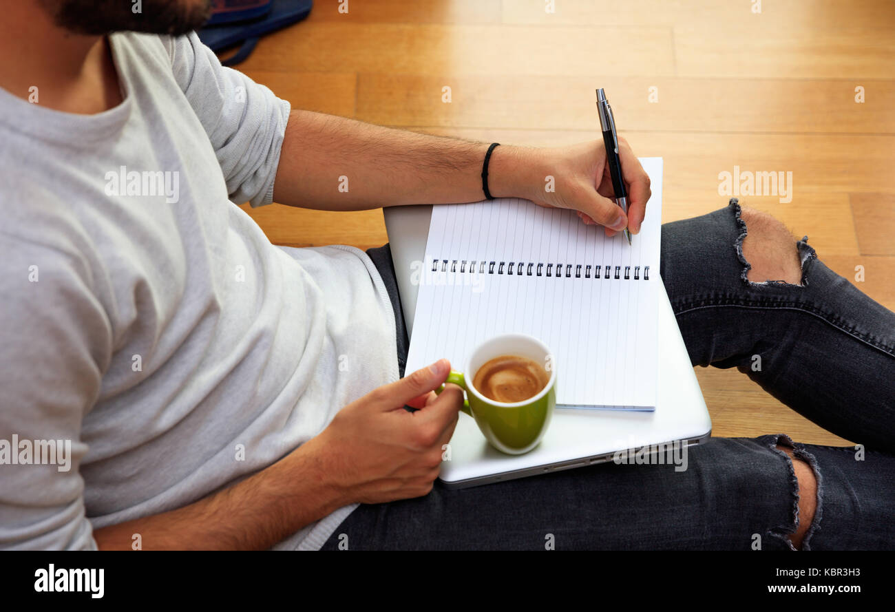 Modern workspace at home. Young left handed man making notes, sitting ...