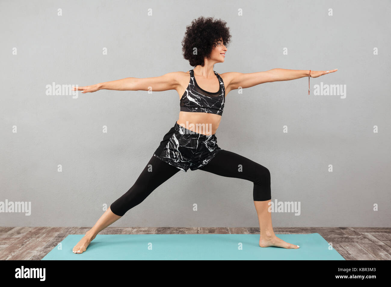 Picture of pretty curly fitness woman make sport yoga exercises over ...