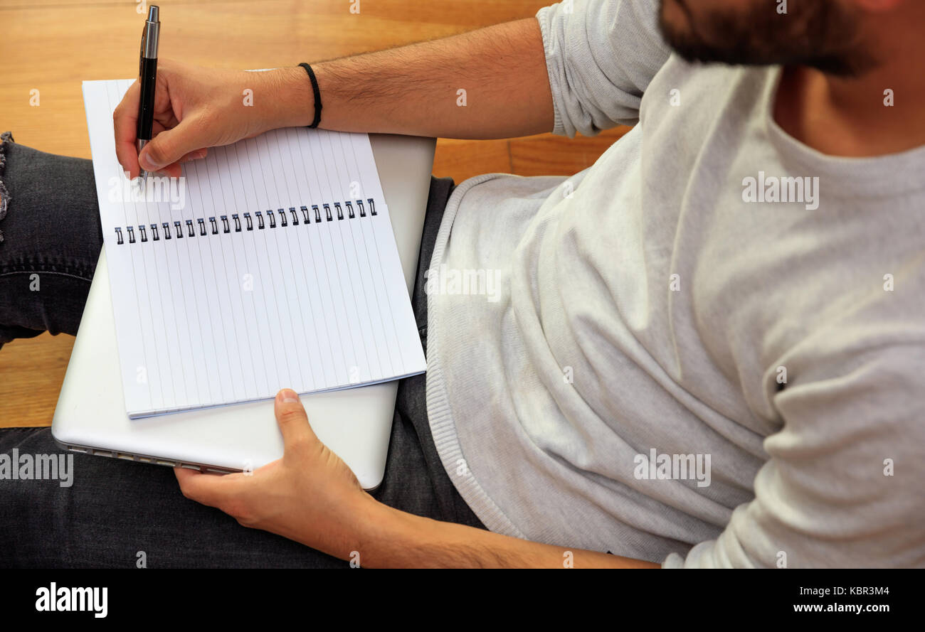 Modern workspace at home. Young man making notes, sitting on wooden ...