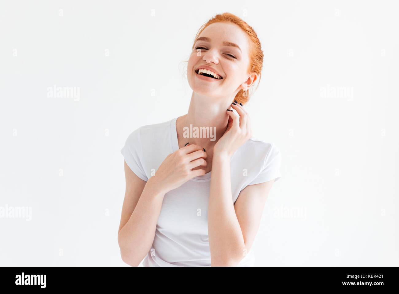 Laughing ginger woman in t-shirt looking at the camera over white ...