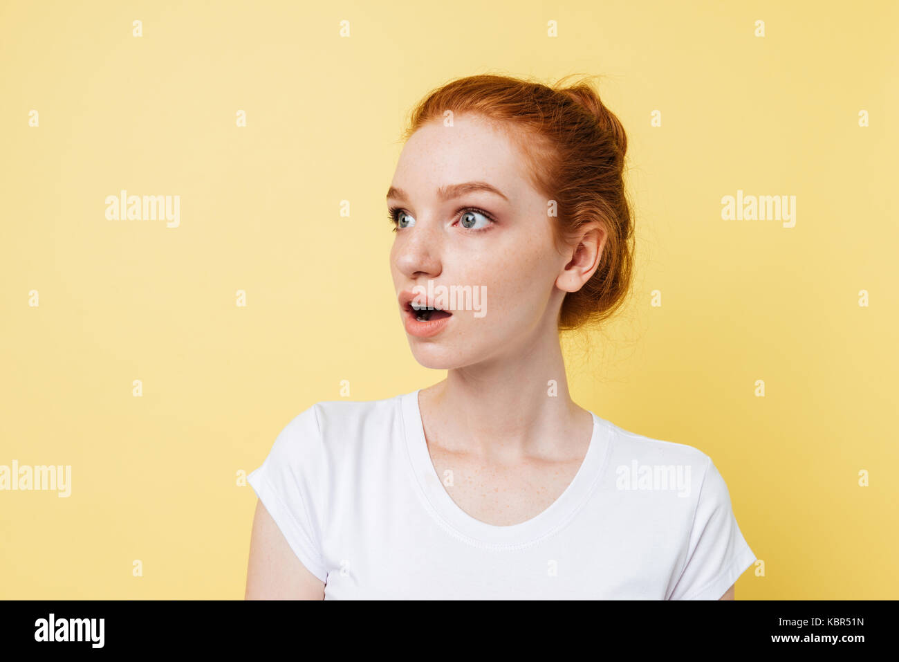 Shocked ginger girl looking away over yellow background Stock Photo - Alamy