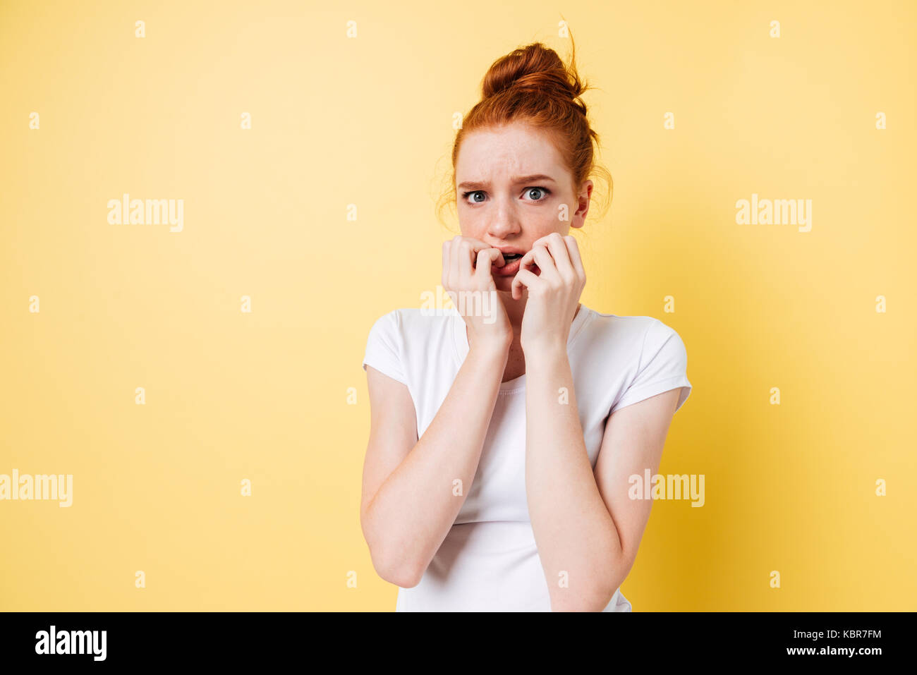 Scared ginger woman in t-shirt over yellow background Stock Photo - Alamy