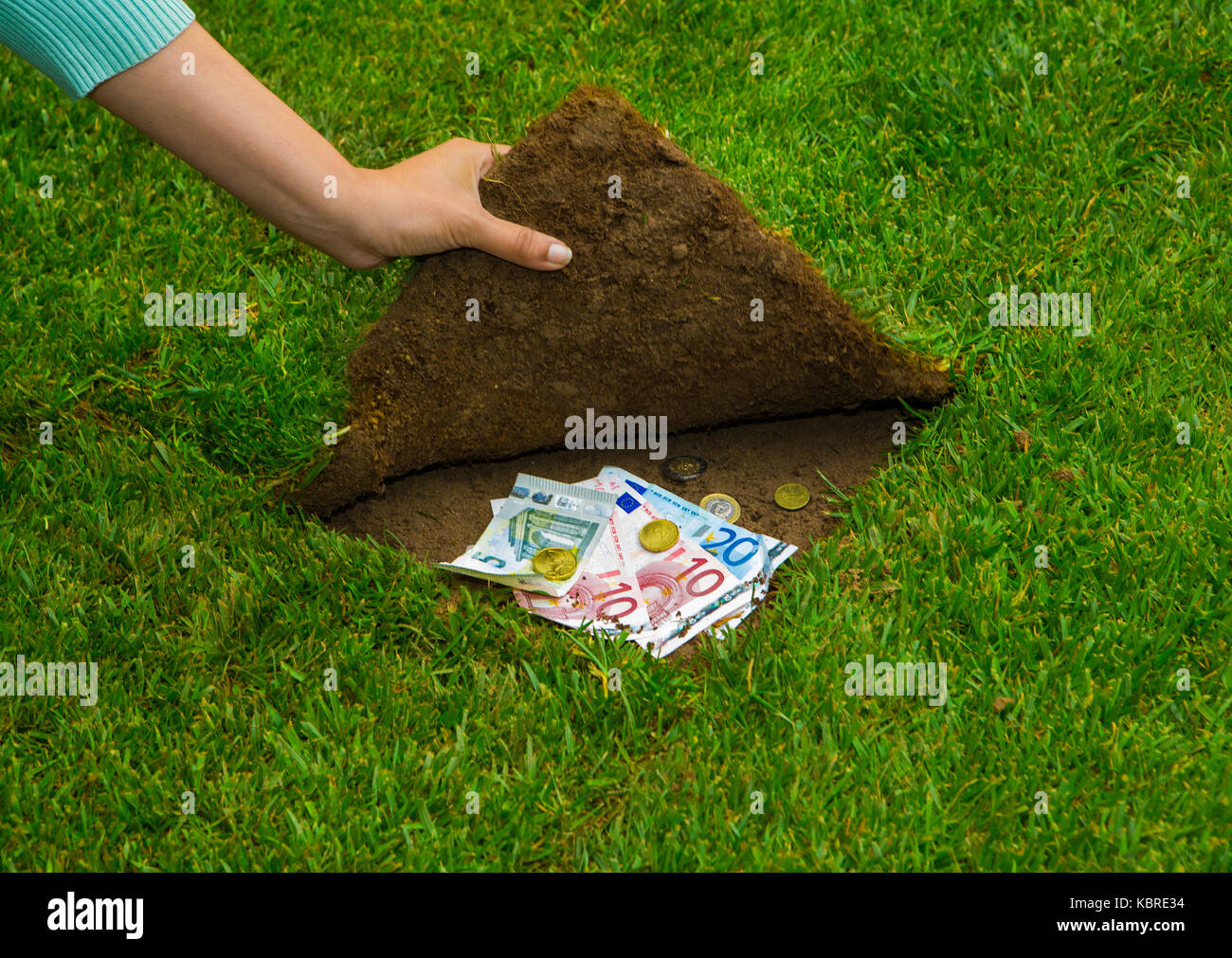 Finances concept, hands hiding money under the grass Stock Photo - Alamy