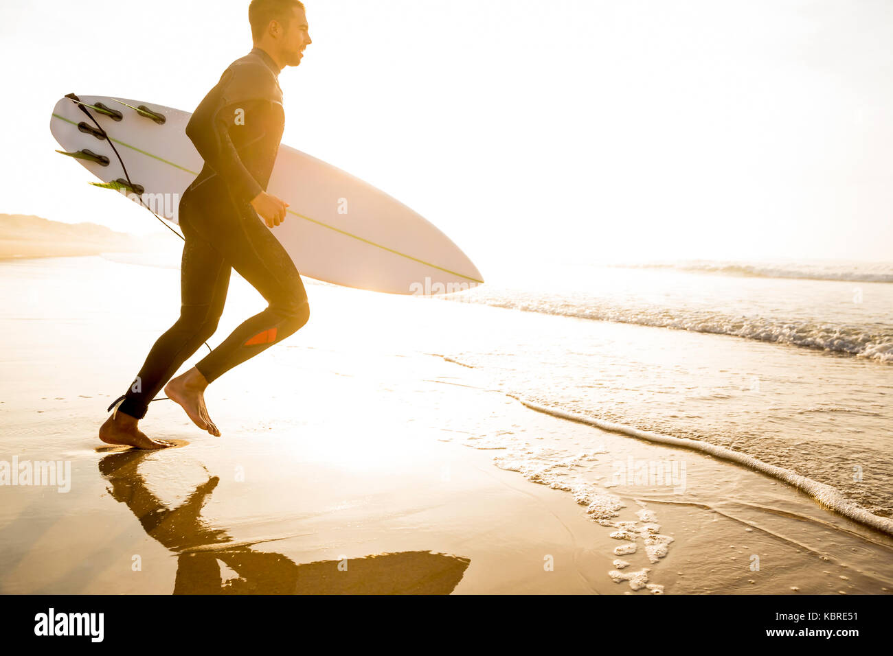 A surfer with his surfboard running to the waves Stock Photo - Alamy