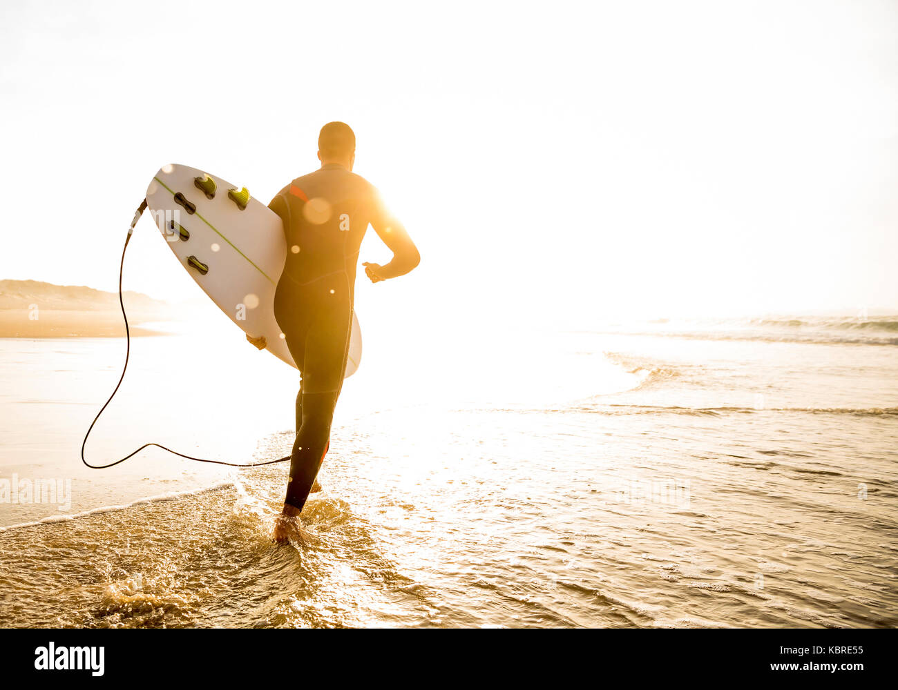 A surfer with his surfboard running to the waves Stock Photo - Alamy