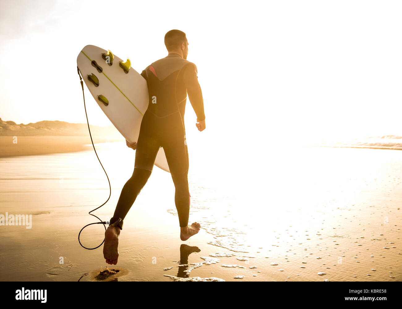 A surfer with his surfboard running to the waves Stock Photo - Alamy