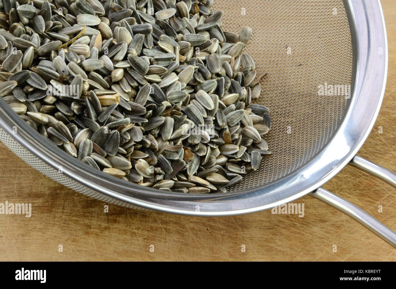 Sunflower seeds in metal sieve on wooden chopping board Stock Photo - Alamy