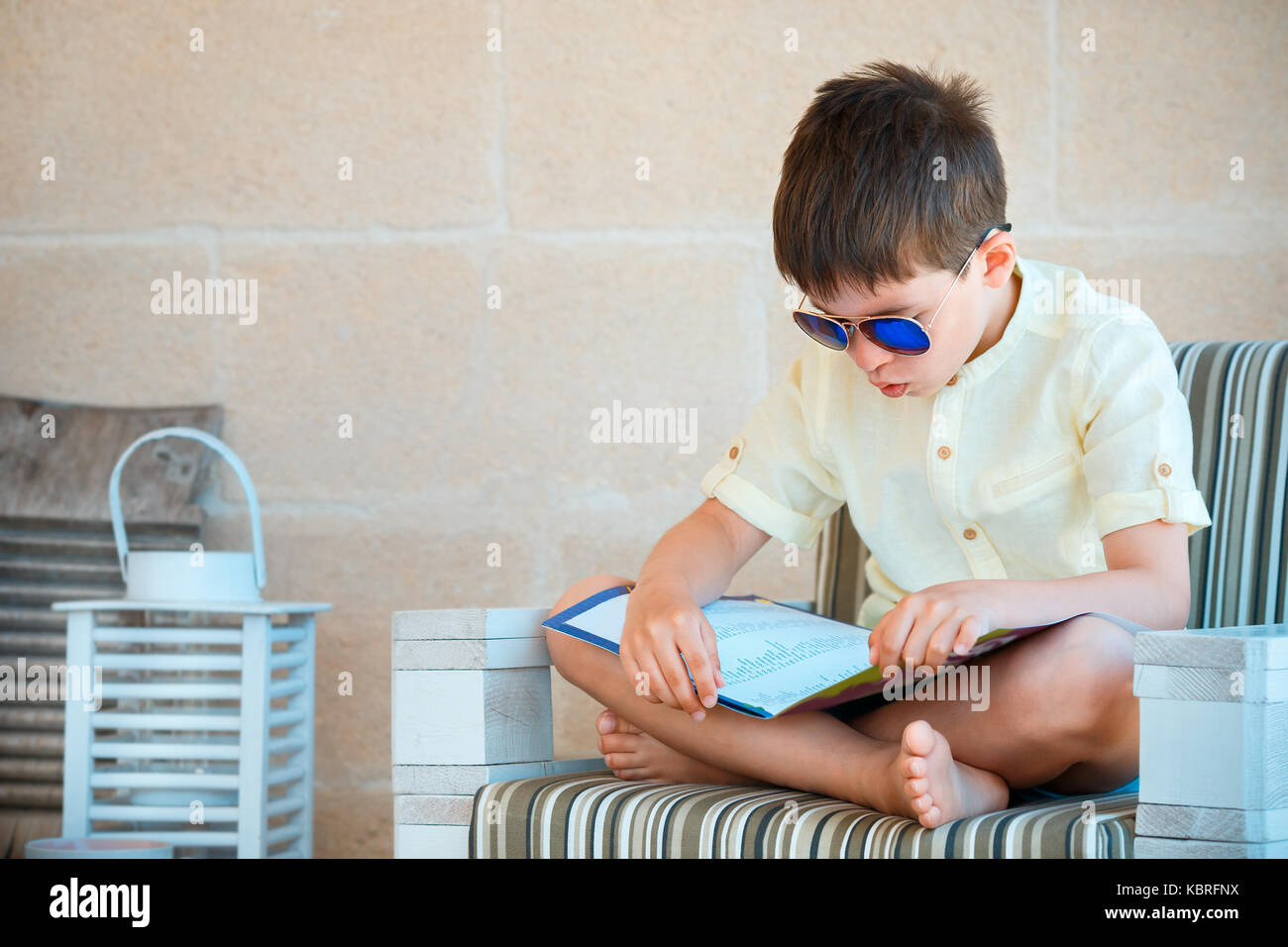 Young boy reading a book on outdoor terrace Stock Photo - Alamy